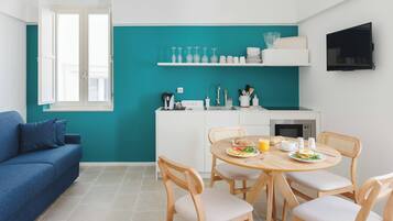 Cozinha moderna com paredes verde-água, armários brancos e uma área de jantar com cadeiras e mesa de madeira.