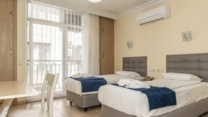 Quarto de hotel com duas camas, uma mesa de jantar e uma cadeira.