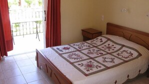 Quarto com cama, mesa de cabeceira e janela com cortinas.