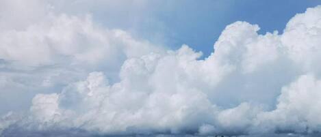 Visão do céu com nuvens e um corpo d'água ao longe.
