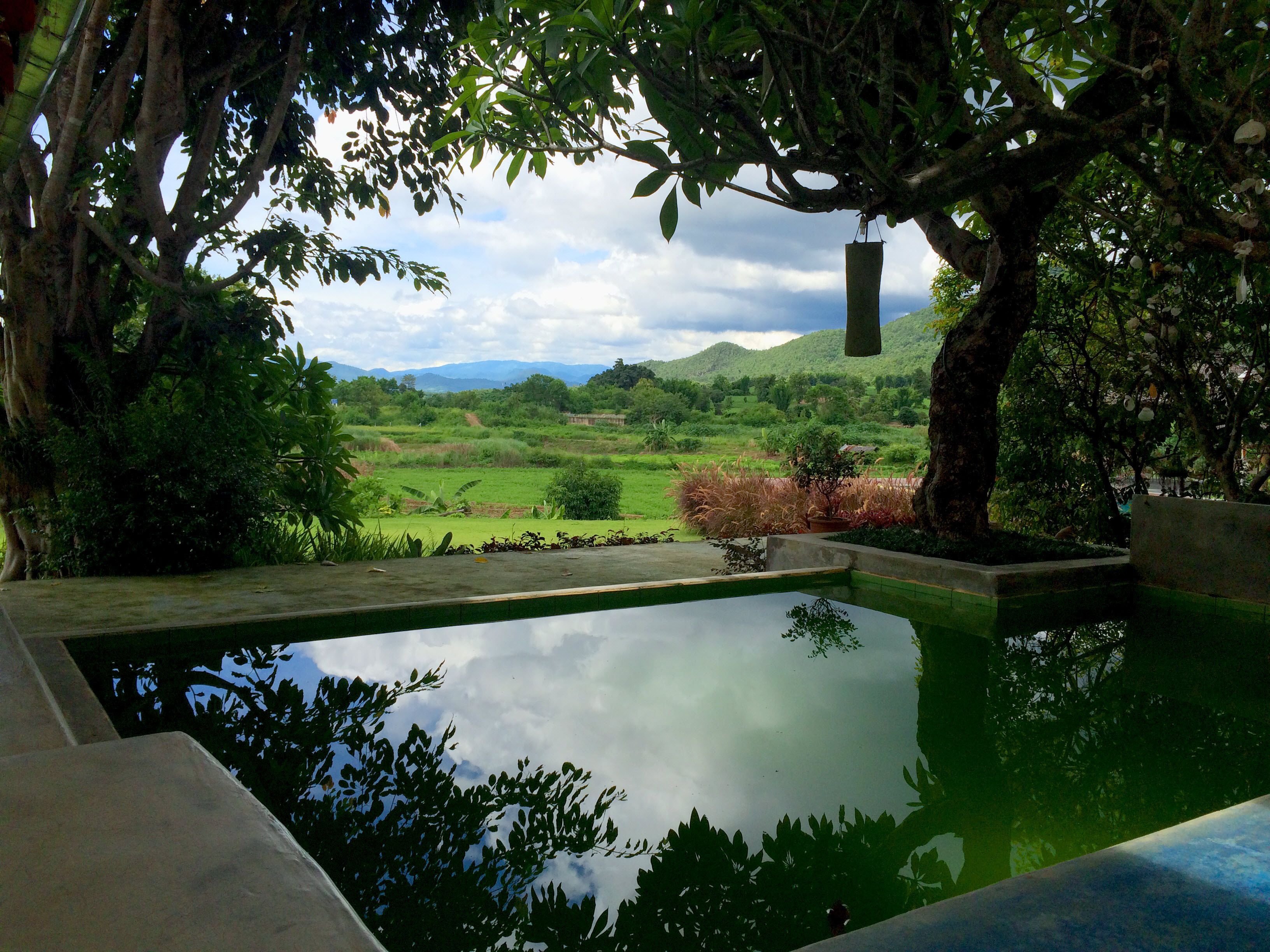 Uma área de piscina ao ar livre tranquila, com vista para uma paisagem verde exuberante e colinas distantes.