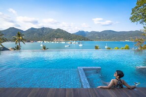 Piscina com vista para barcos e montanhas.