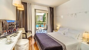 Quarto de hotel com cama, mesa de cabeceira, televisão e vista para a área da piscina.