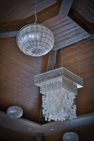 Teto com painéis de madeira, luminárias esféricas penduradas e luminária pendente geométrica.