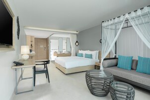 Quarto de hotel moderno com cama, sofá, escrivaninha e cadeiras de vime.