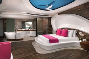 Um quarto moderno com cama curva, janela grande e ventilador de teto.