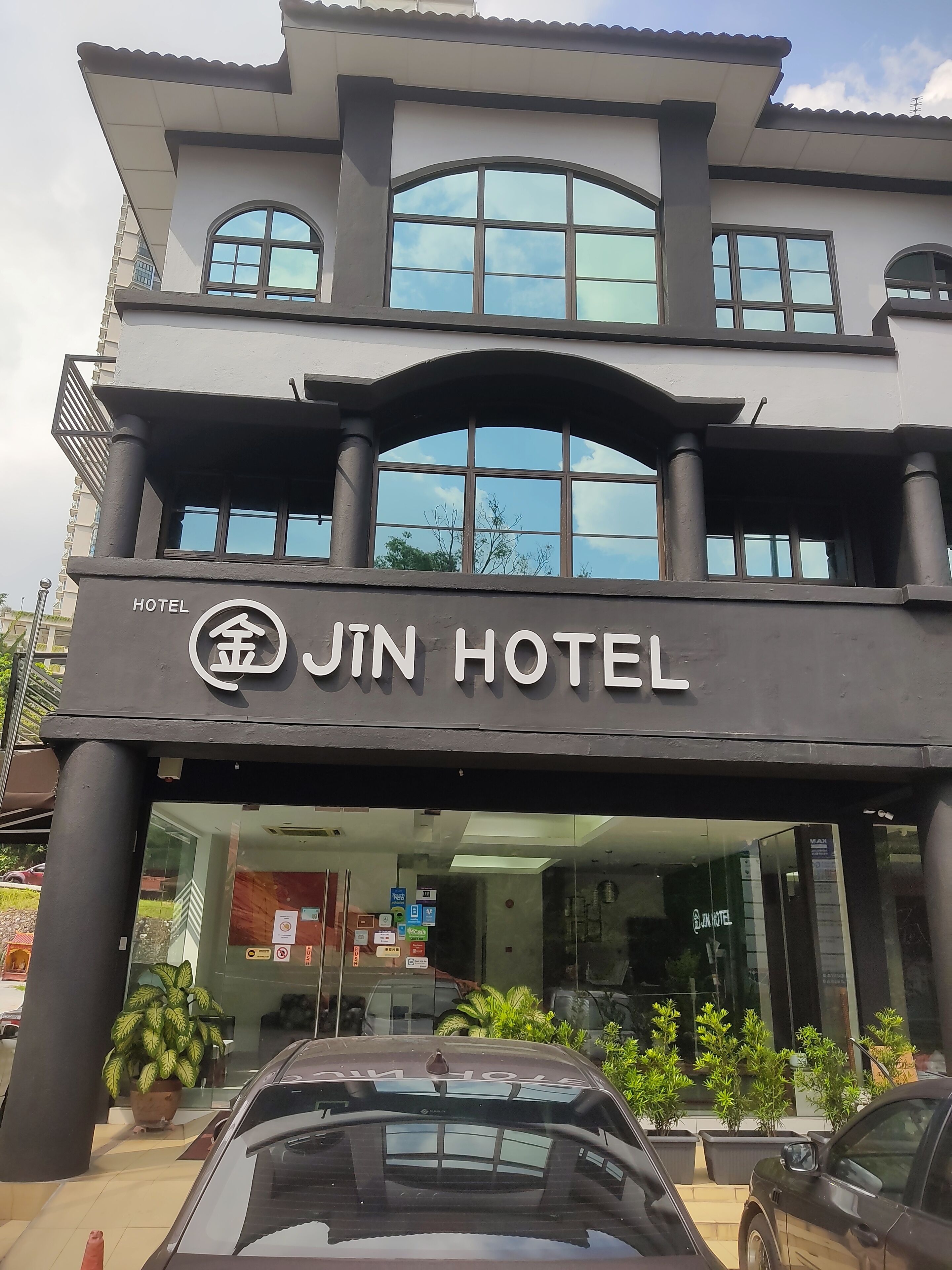 Um edifício de dois andares com a placa "JIN HOTEL" em destaque.