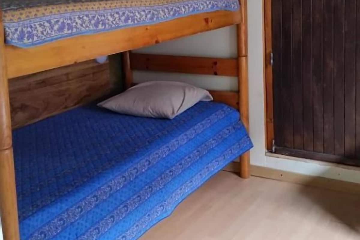 Uma cama beliche com colcha estampada e um travesseiro.