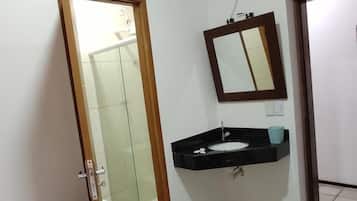 Quarto pequeno e limpo, com uma cama, banheiro com pia e espelho, e aparelho de ar condicionado.