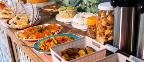 Buffet variado com diversos pratos, incluindo um bolo com fatias de limão, uma tigela de arroz e um recipiente com frutos secos.