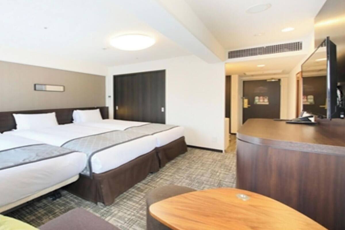 Quarto de hotel com duas camas, um espaço de estar pequeno e uma receção.