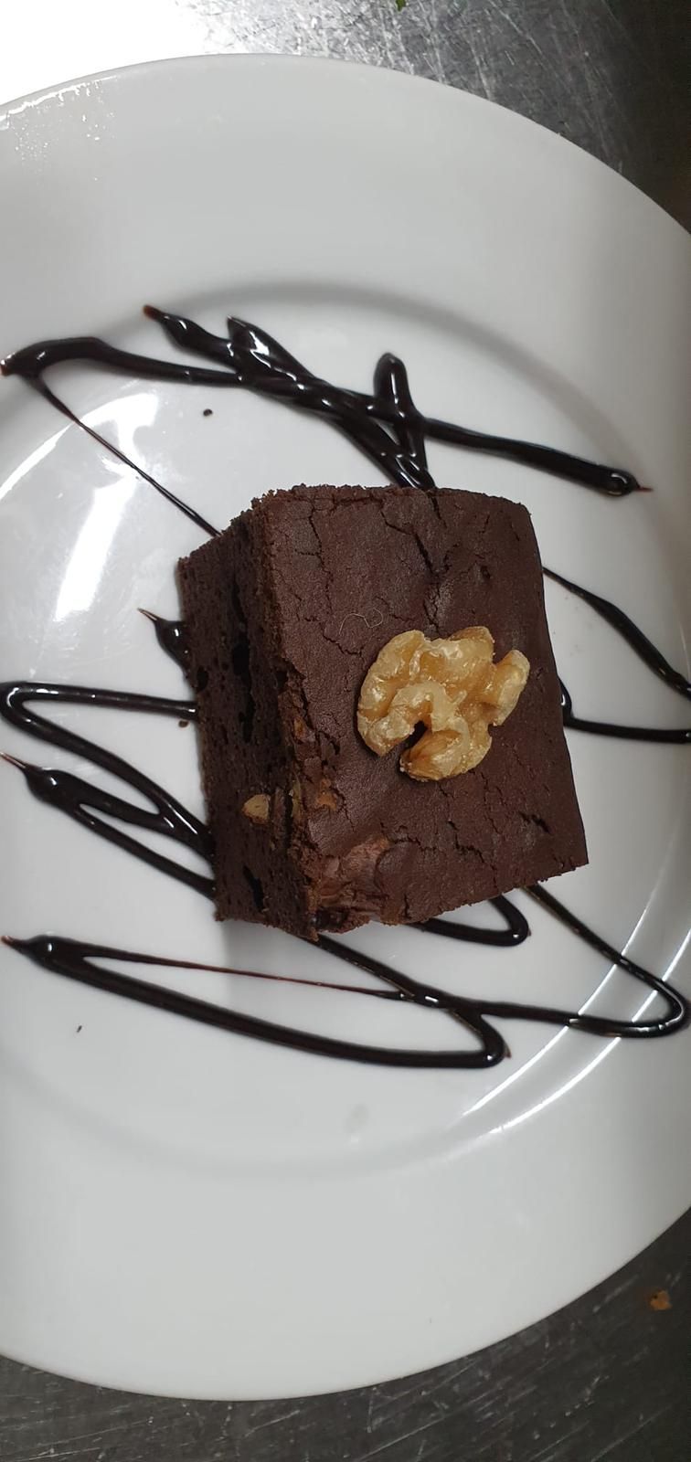 Sobremesa em um prato branco com calda de chocolate.