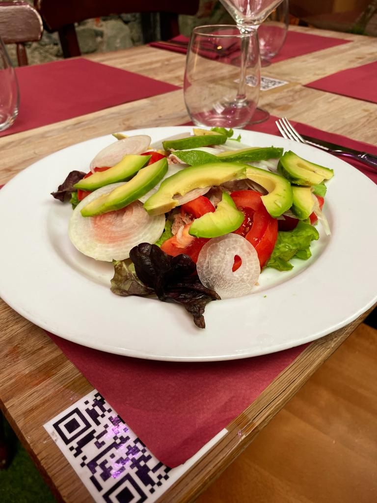 Prato branco com salada sobre uma mesa de madeira.