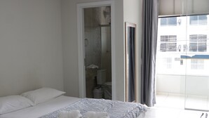 Quarto de hotel com cama, banheiro com chuveiro e vista para o exterior.