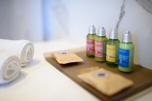Casa de banho com toalha, bandeja com produtos de higiene e parede de mármore.