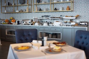 Um buffet de café da manhã com diversas opções de comida e um espaço para café.