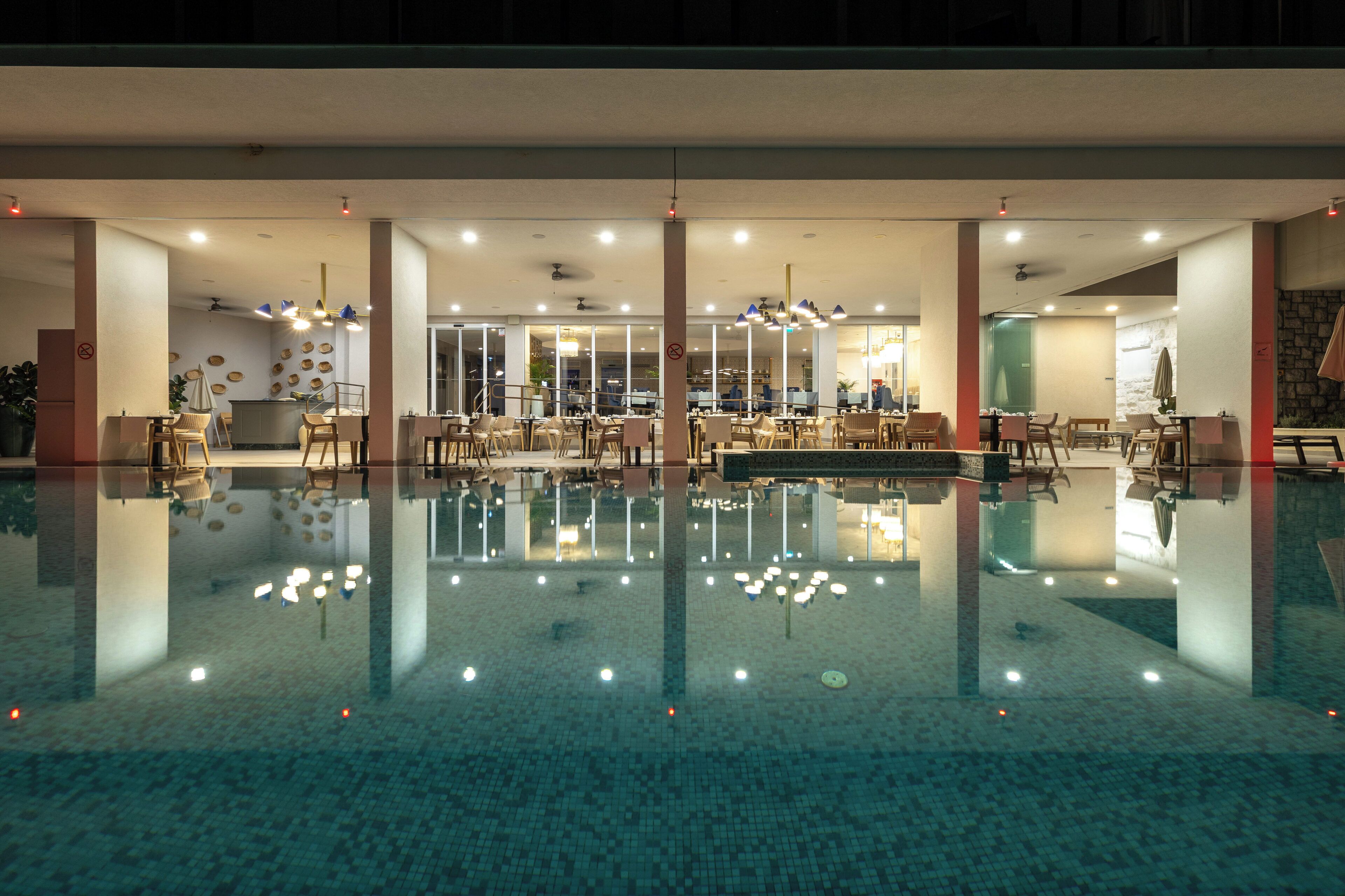 Piscina ampla e interna com vista para o bar e área de estar.