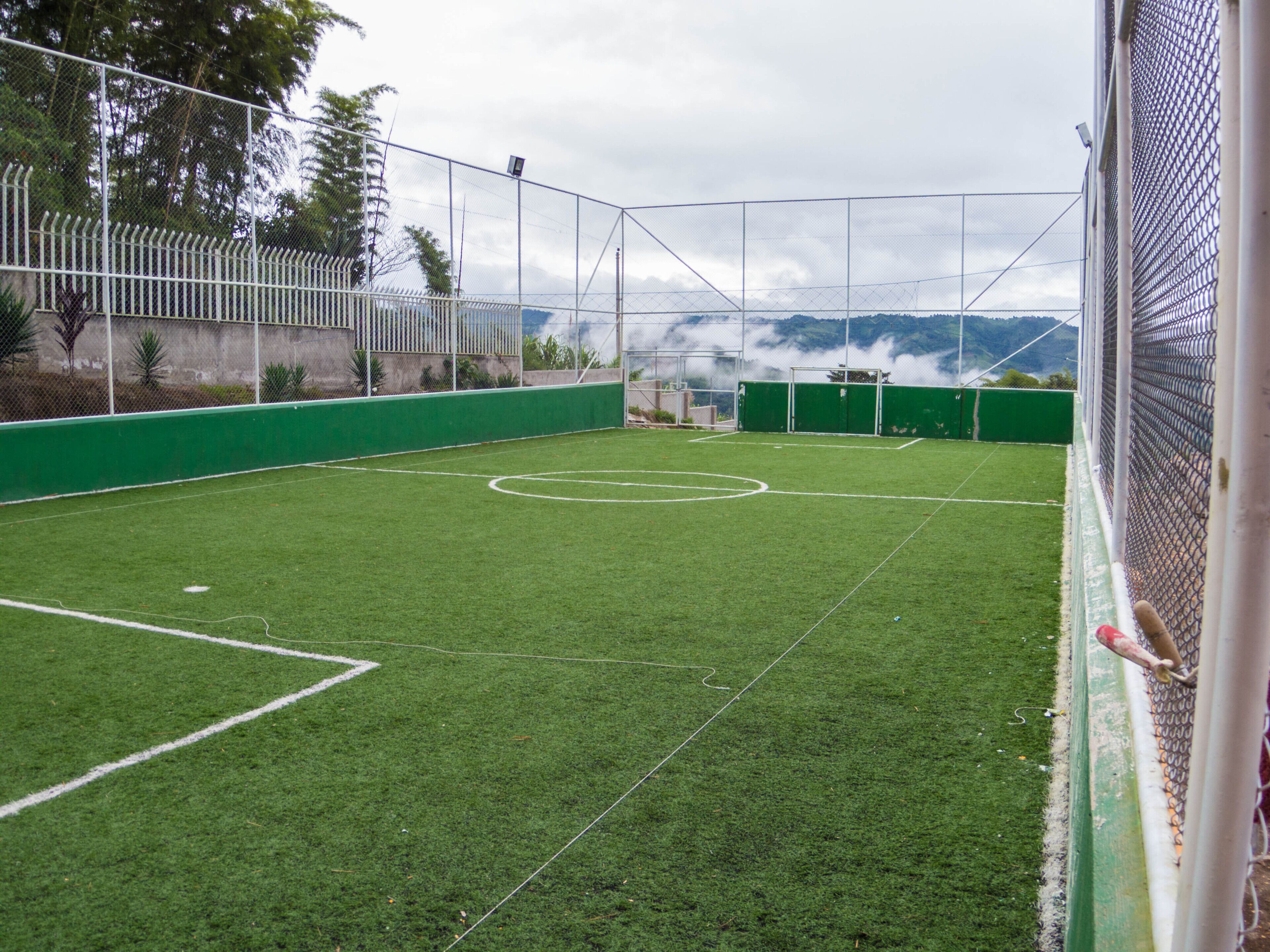 Um campo de futebol com postes de gol e uma cerca verde.