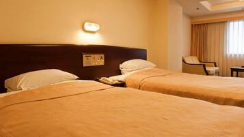 Quarto de hotel com duas camas, uma mesa de cabeceira com telefone e uma cadeira.