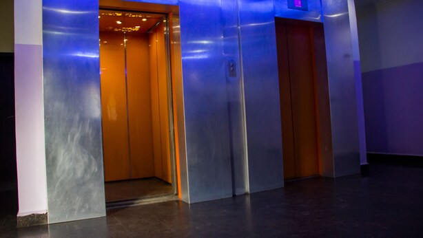 Um elevador moderno com paredes metálicas e um painel digital.