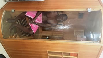 Uma sauna com interior em madeira, estrutura de vidro e um banco.