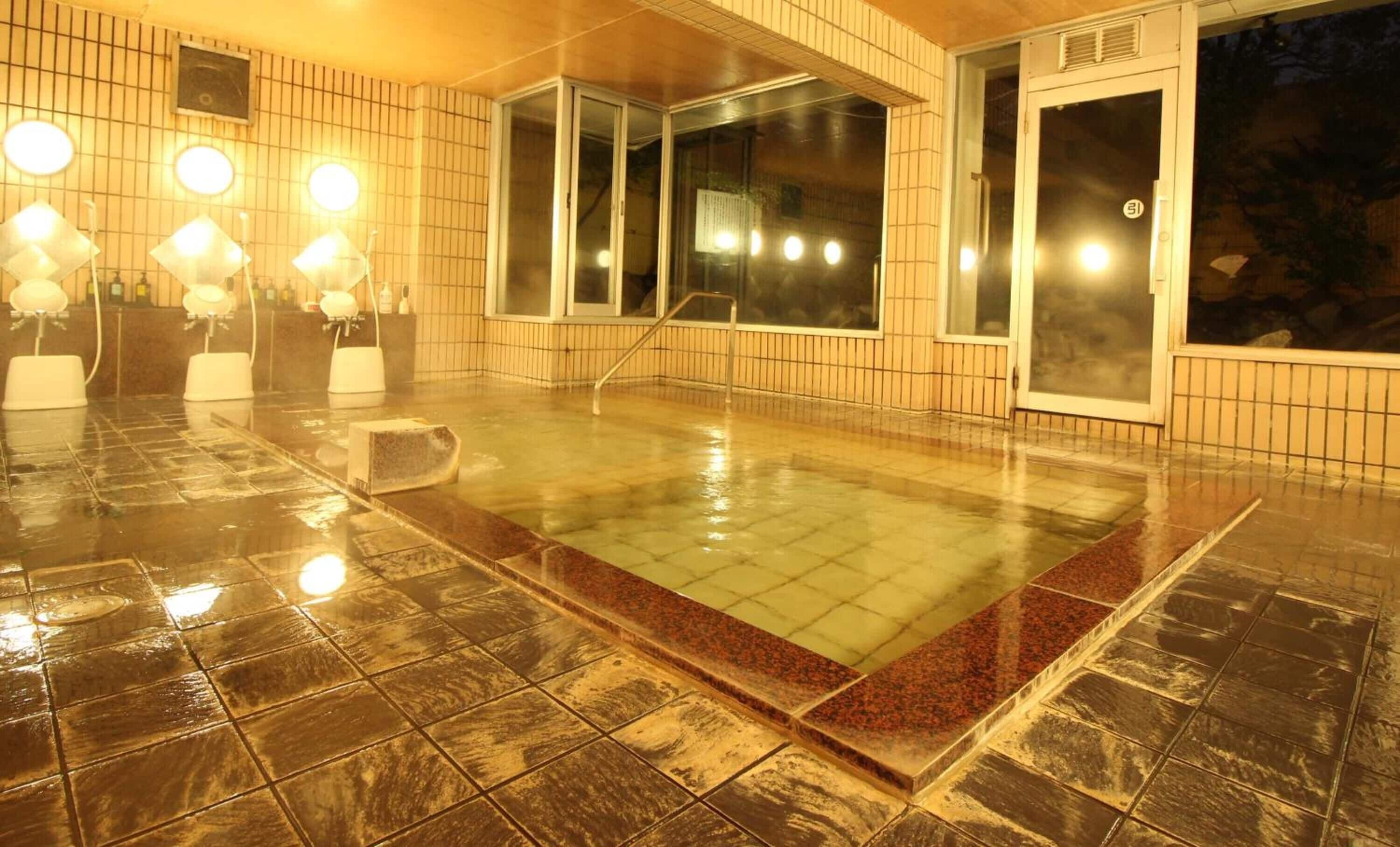 Uma área de hidromassagem com piso em azulejo, divisória de vidro e janela.