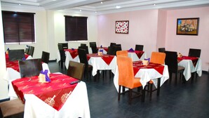 Uma sala de jantar com várias mesas e cadeiras, dispostas em fileiras.