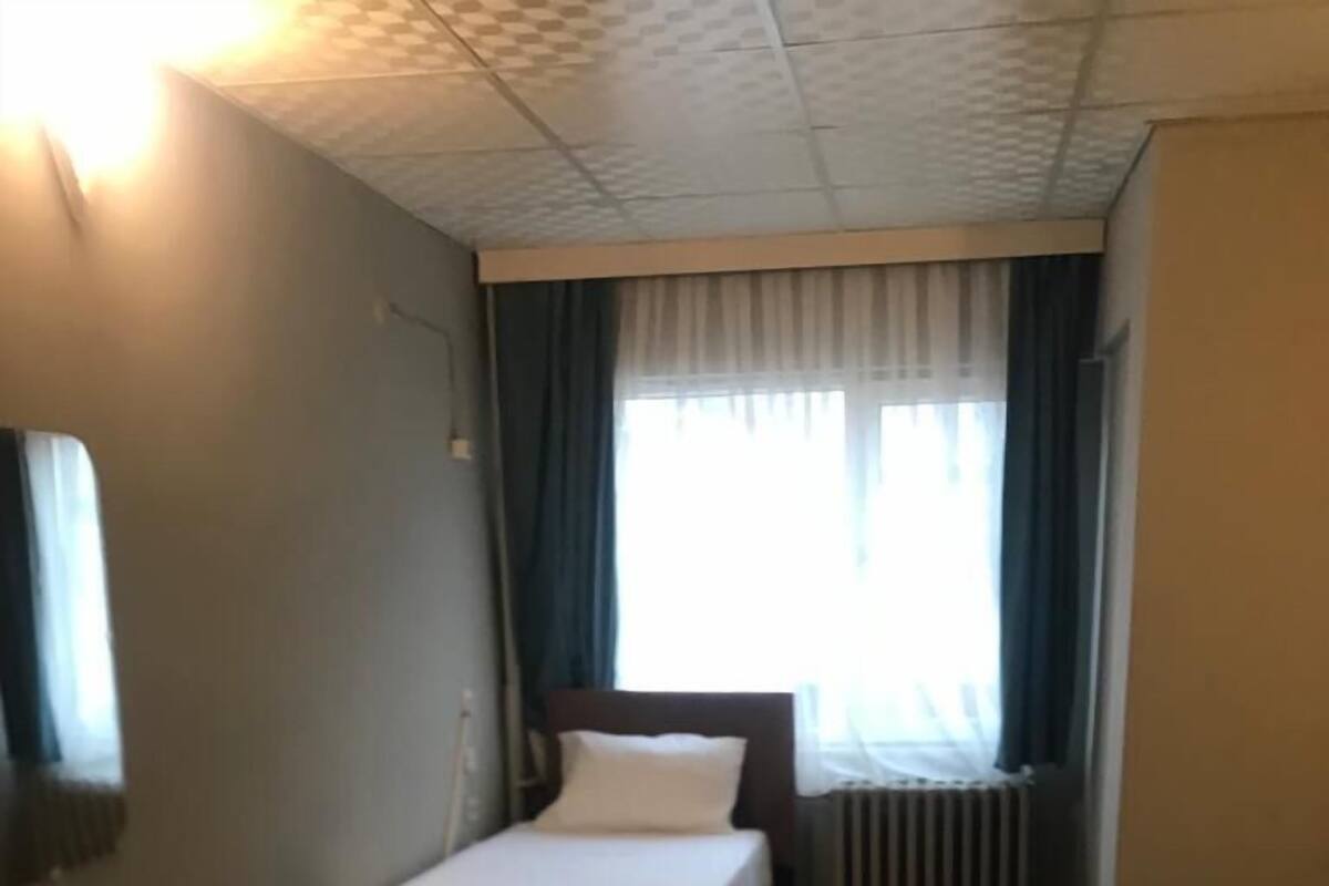 Quarto de hotel com duas camas, uma escrivaninha e uma janela com cortinas.