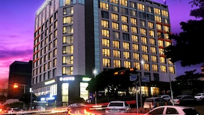 Um hotel moderno com vários andares, janelas iluminadas e uma placa de destaque.