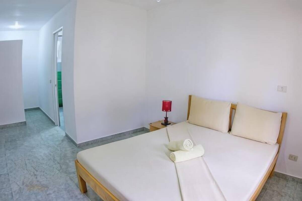 Quarto com uma cama, mesa de cabeceira e abajur vermelho.