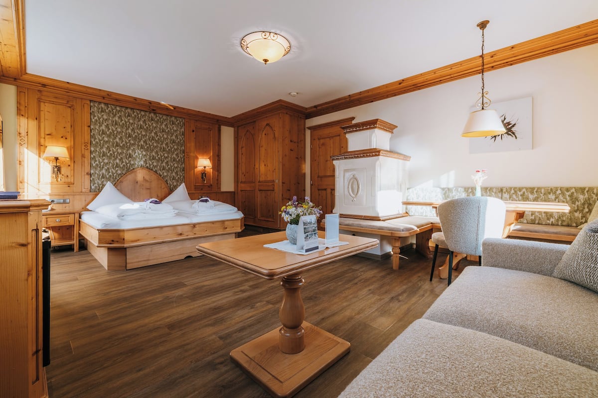Um quarto com uma cama, um sofá, uma mesa e painéis de madeira.