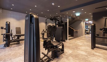 Uma academia moderna com diversos equipamentos de exercício, uma escada e um espelho fixado na parede.