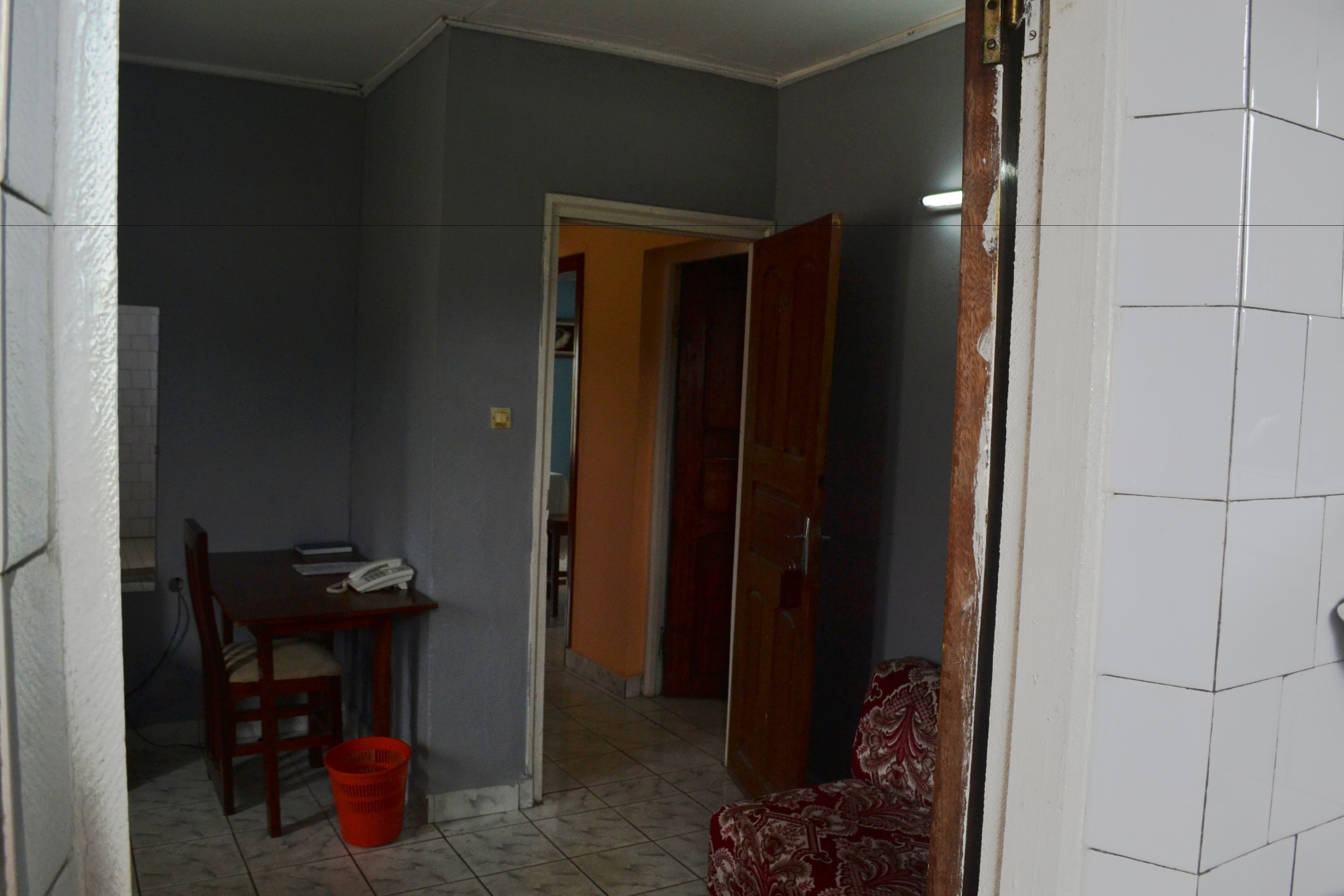Um quarto com uma mesa de jantar, cadeiras, uma cesta vermelha e um sofá estampado.