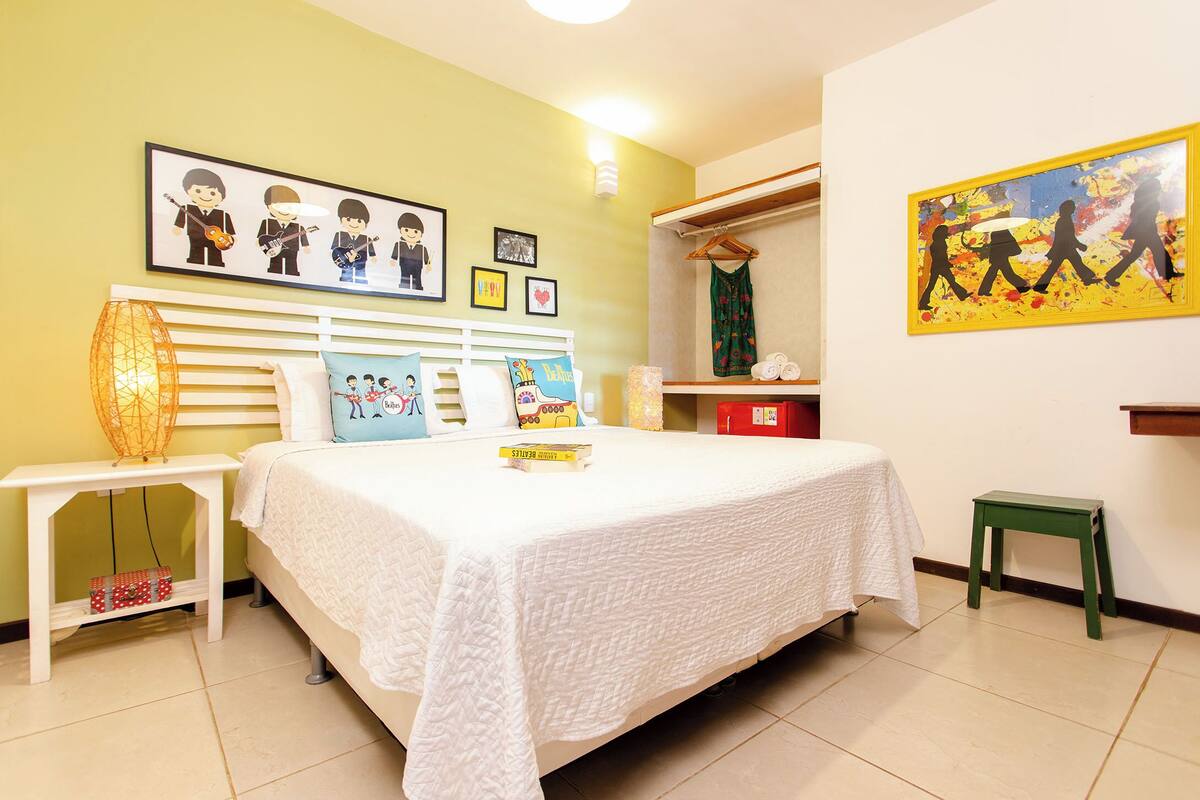 Quarto bem arrumado com cama, mesas de cabeceira e obras de arte na parede.