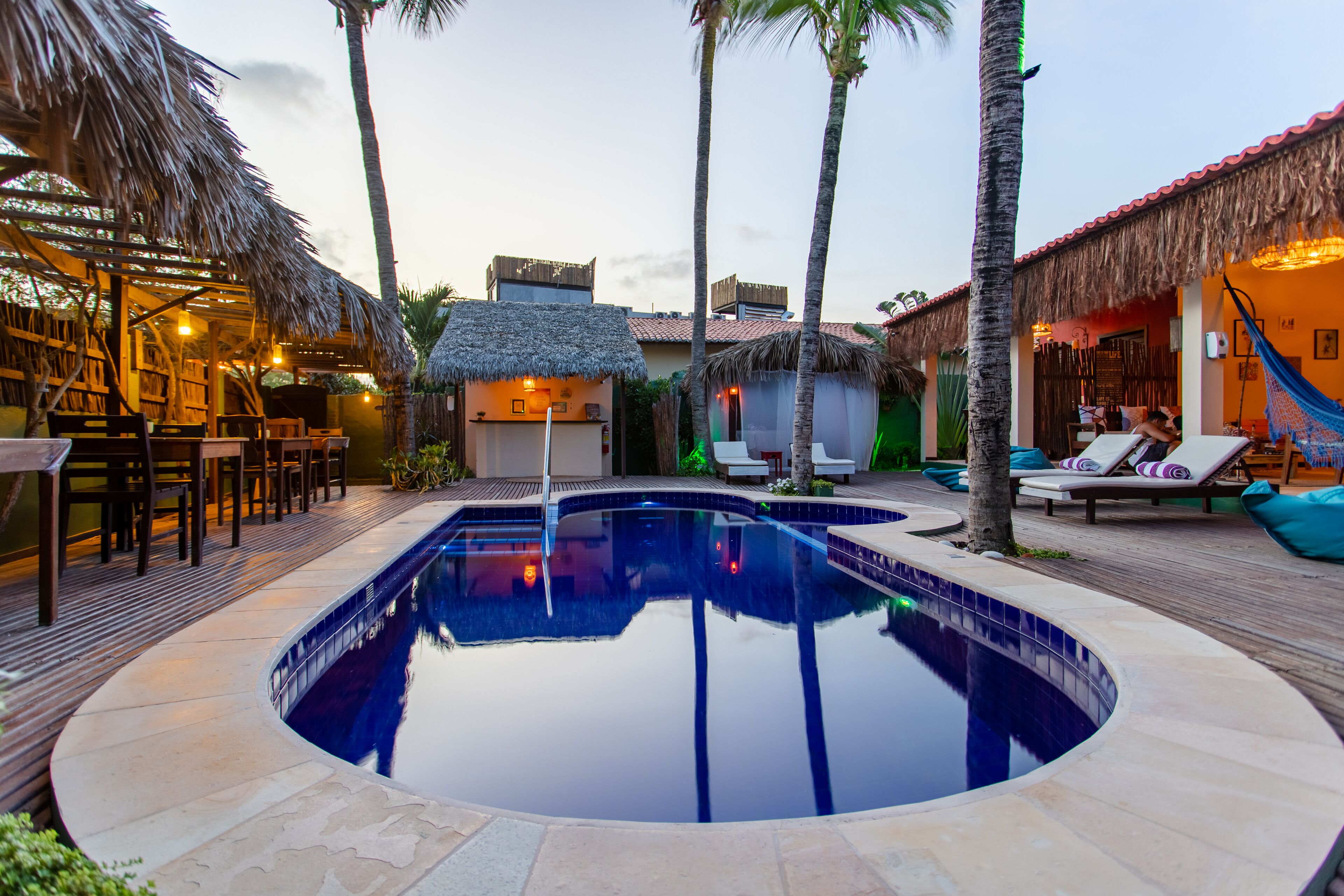 Área de piscina com espreguiçadeiras e um bar.