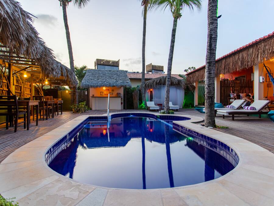 Área de piscina com espreguiçadeiras e um bar.