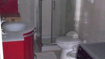 Casa de banho compacta com chuveiro, sanita e máquina de lavar roupa.