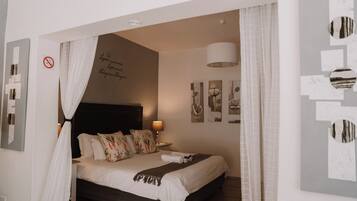 Quarto com cama, mesa de cabeceira, abajur e decoração nas paredes.