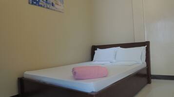 Uma cama de solteiro com estrutura de madeira, roupa de cama branca e toalha rosa.