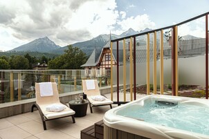 Uma varanda com duas cadeiras de descanso, uma banheira de hidromassagem e vista para as montanhas.