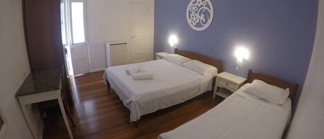 Quarto com duas camas, uma escrivaninha e um ventilador de teto.