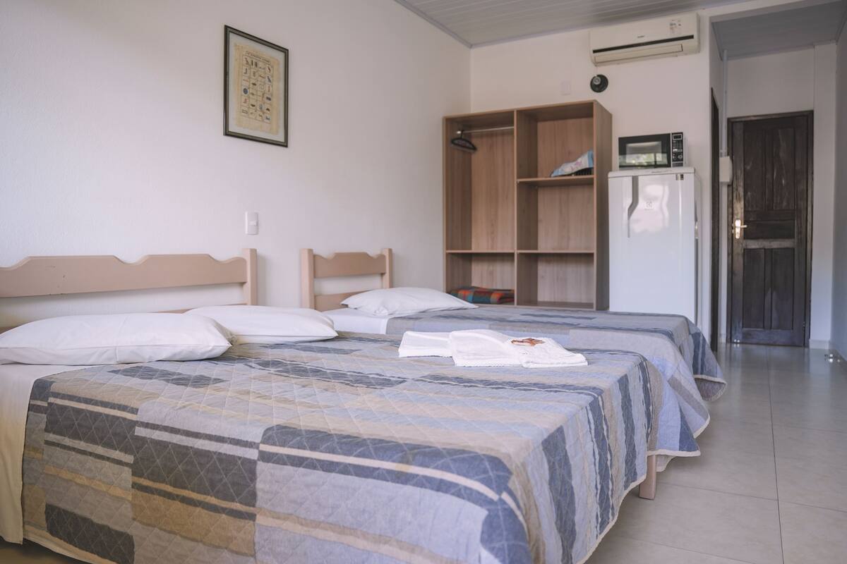 Quarto com cama, guarda-roupa e micro-ondas.