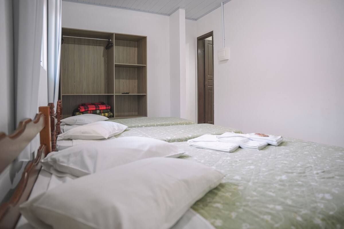 Um quarto com cama, almofadas, guarda-roupa e espelho.