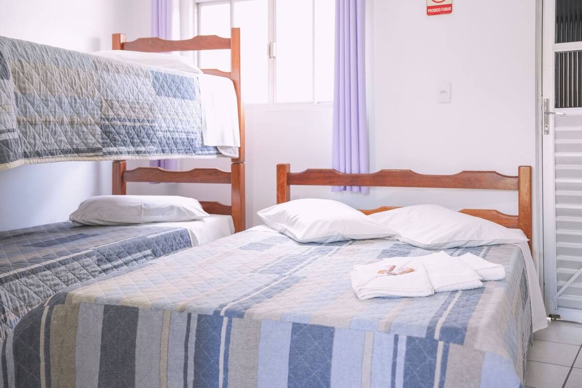 Quarto em dormitório com duas camas, cada uma com colcha acolchoada e travesseiros.