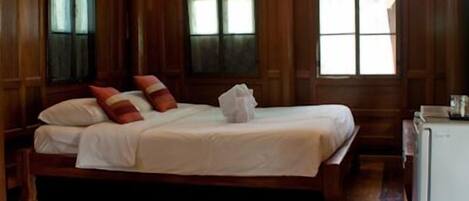 Um quarto com painéis de madeira, uma cama, uma mesinha e um frigorífico.