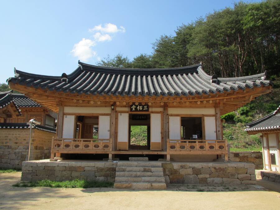 Um pavilhão tradicional coreano com telhado telhado, vigas de madeira e base de pedra.