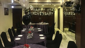 Uma sala de jantar com mesas redondas, cadeiras pretas e balões.