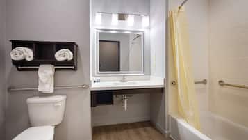 Uma casa de banho moderna com sanita, lavatório e chuveiro. Existem porta-toalhas e um espelho sobre o lavatório.