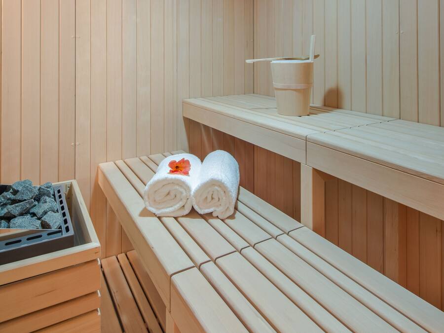 Uma sauna de madeira com bancos, toalhas e um balde.