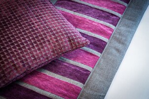 Tapete estampado com padrão xadrez e listras horizontais em tons de rosa e roxo.